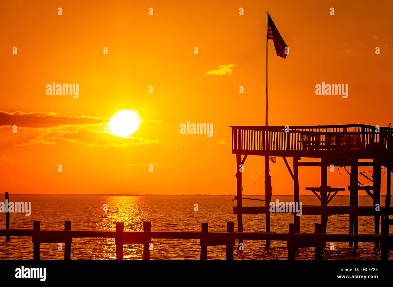 The sun sets behind boat docks and fishing piers on Coden Beach, Dec ...