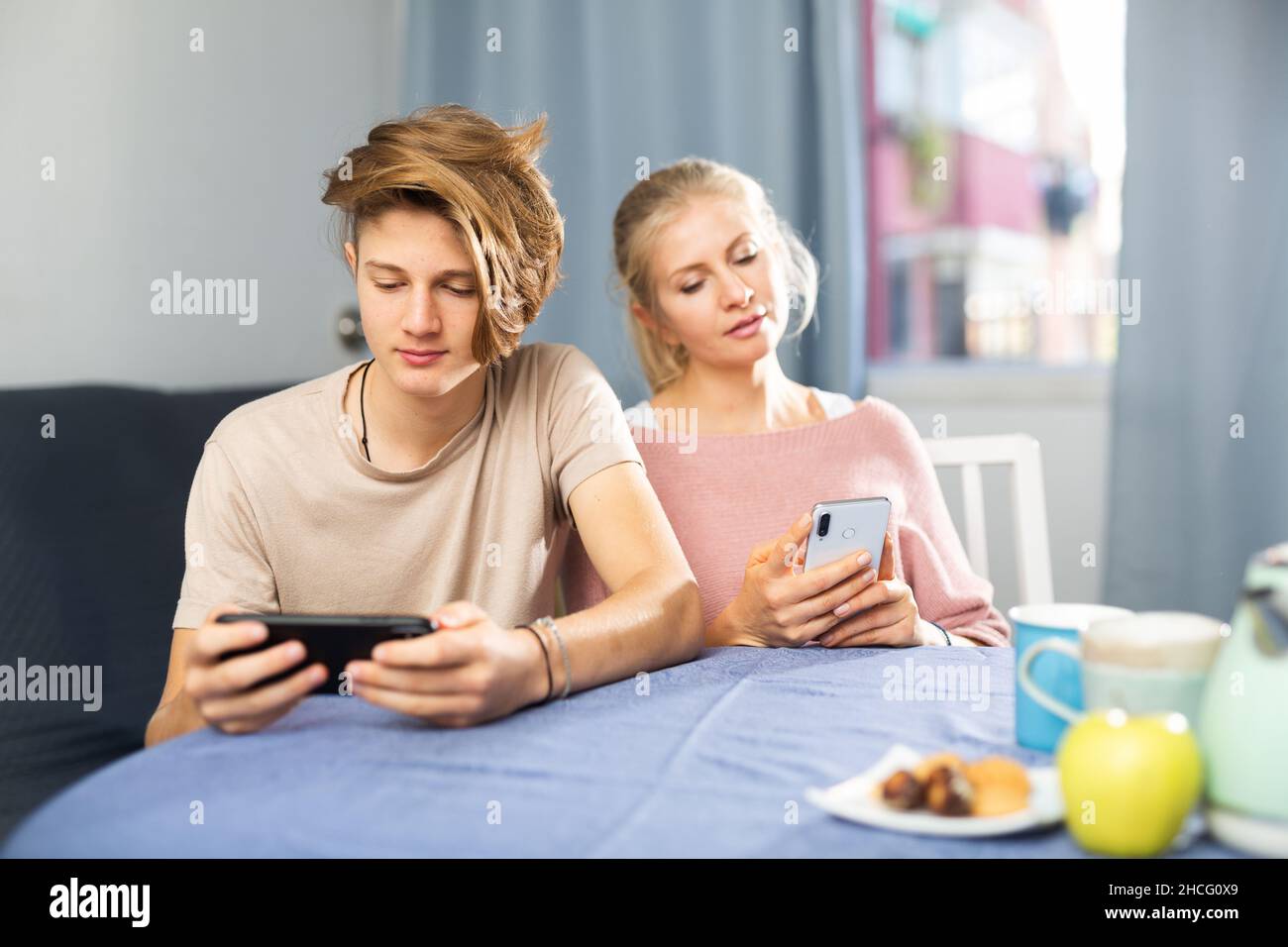 Mother and son using phones during breakfast Stock Photo - Alamy