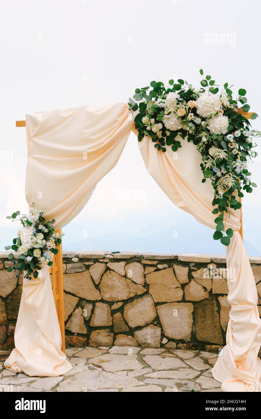 Rectangular wedding arch decorated with fabric and flowers stands on ...