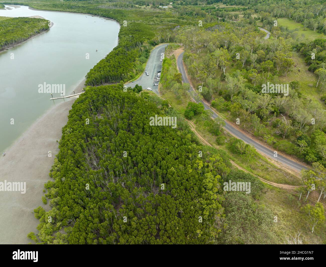 Drone aerial up a creek at low tide showing boat ramp and jetty with ...