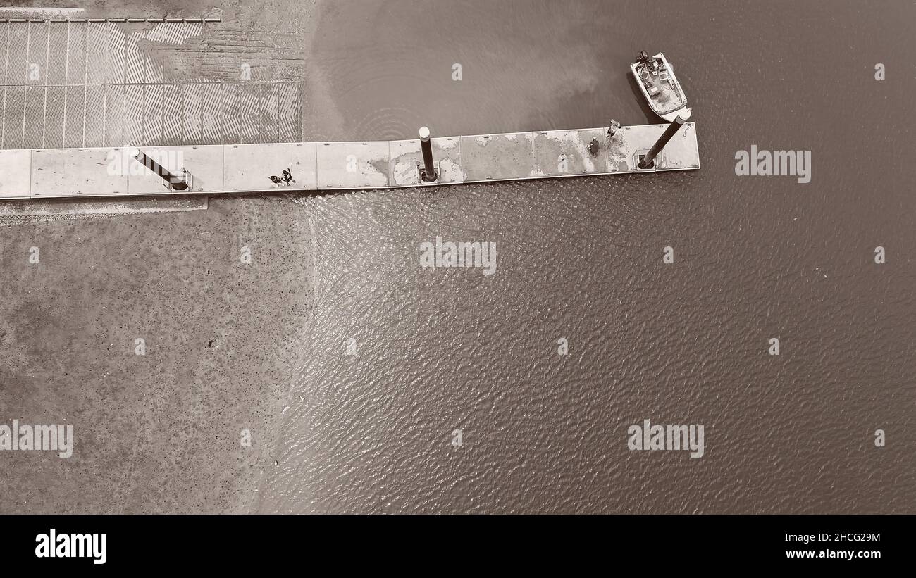 Unidentifiable people on a jetty with a boat tied up near the launching ...