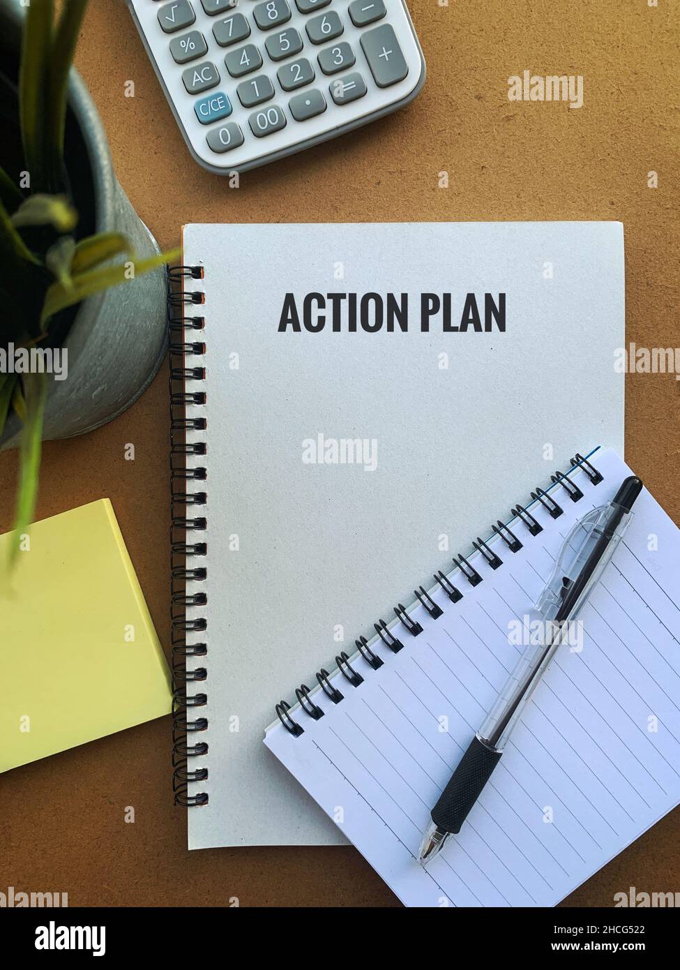 Image with action plan text on a note pad with pen, plant, calculator ...