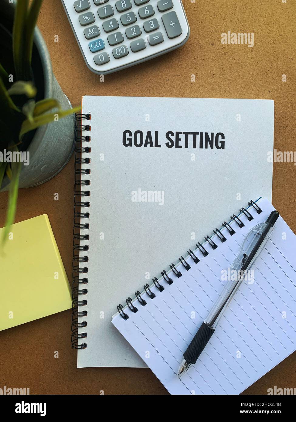 Image with goal setting text on a notepad with pen, plant, calculator ...