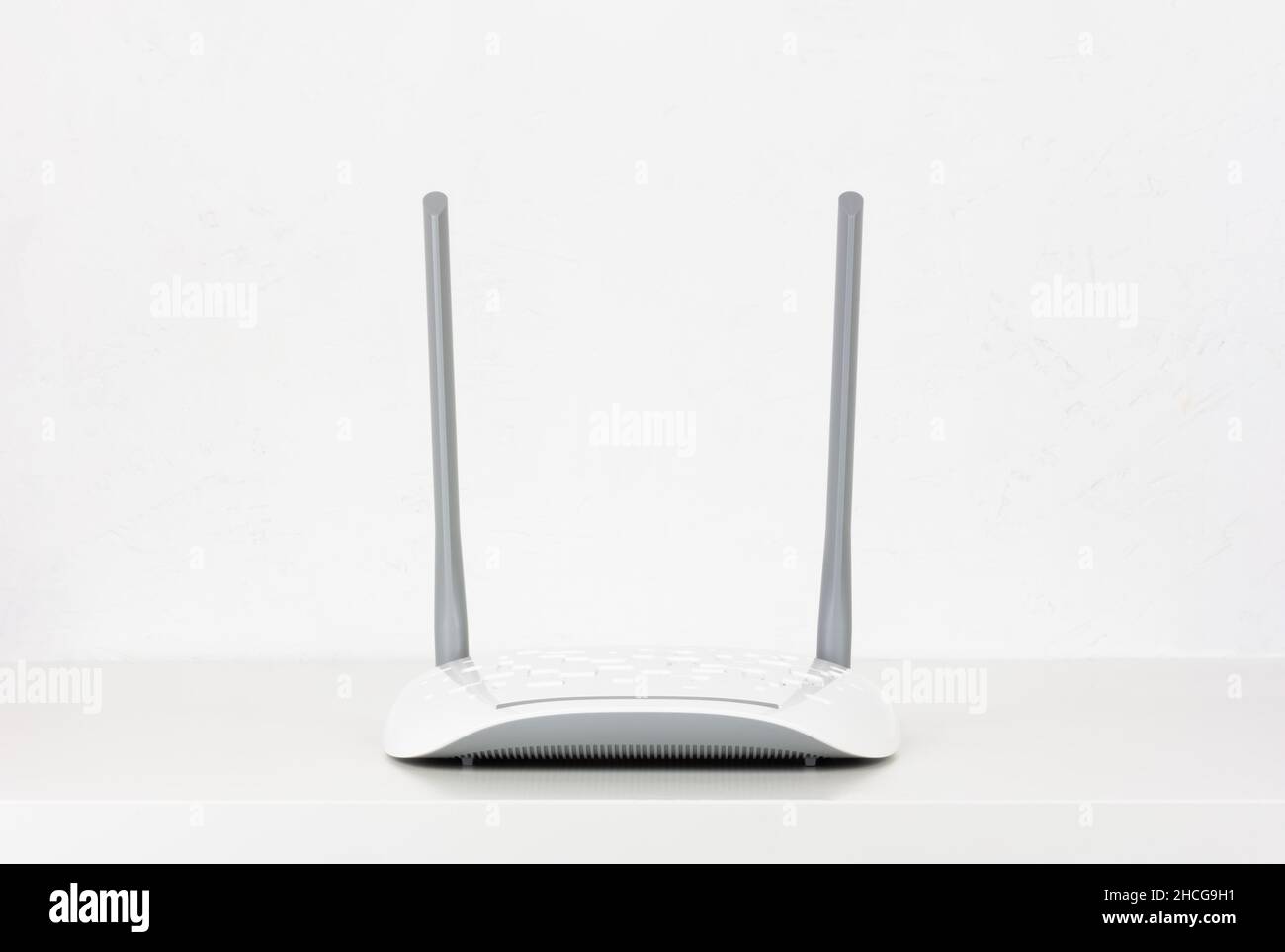 new white Wi fi router on a table against a white wall with a copy ...