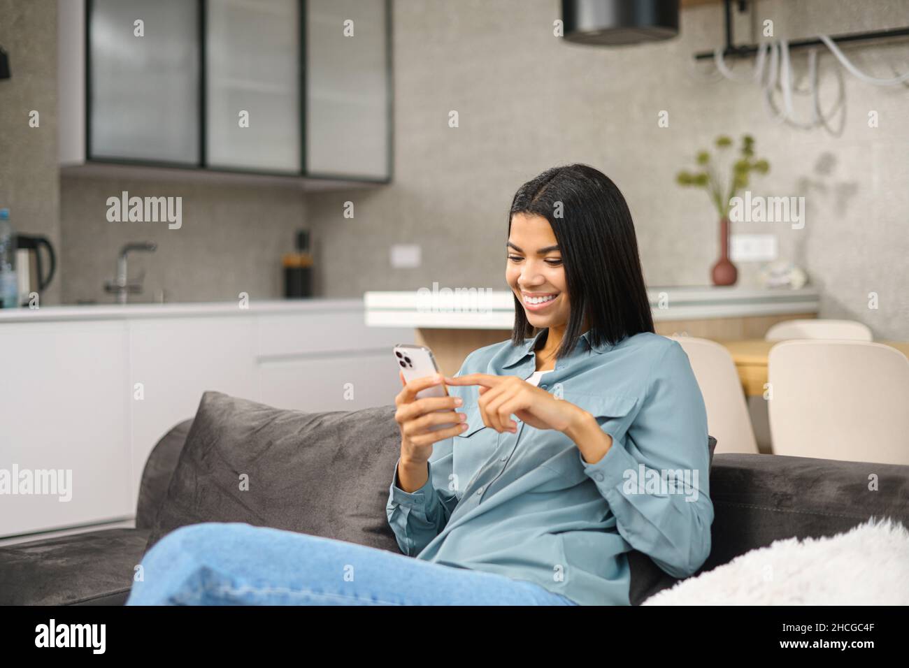 Glad brunette woman spending leisure with a smartphone, checking emails, shopping online ...