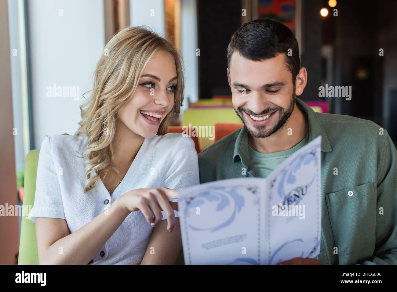 cheerful woman pointing with finger near smiling boyfriend choosing ...