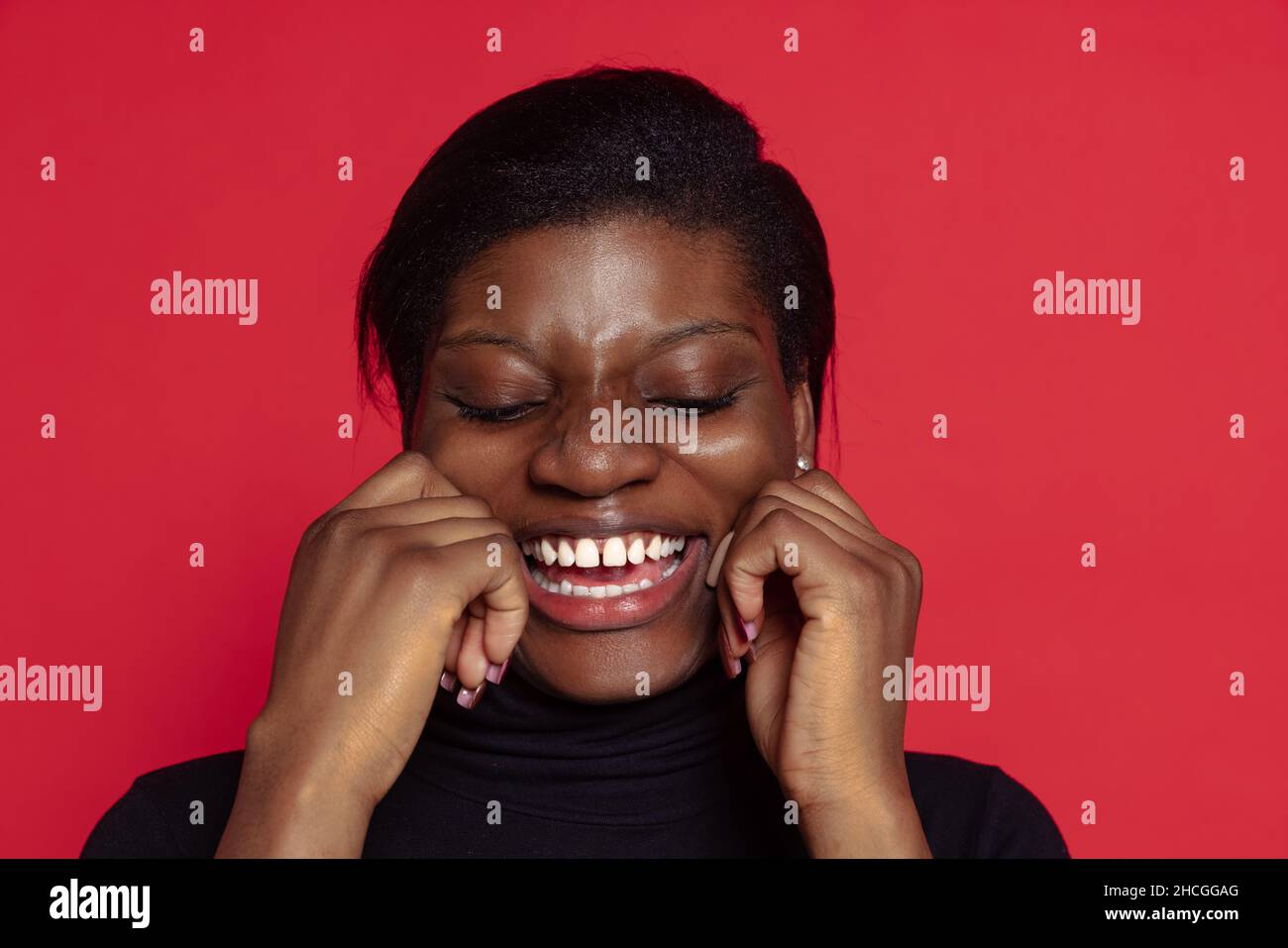 Portrait of young dark skinned girl laughing isolated on dark red ...
