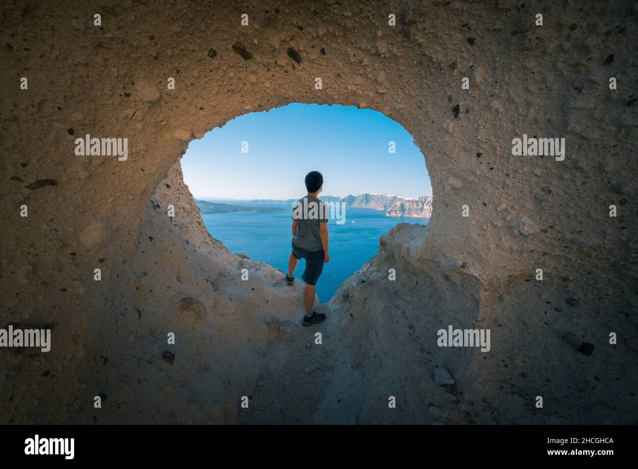 An Asian man standing in a cave on the edge of an island cliff in ...