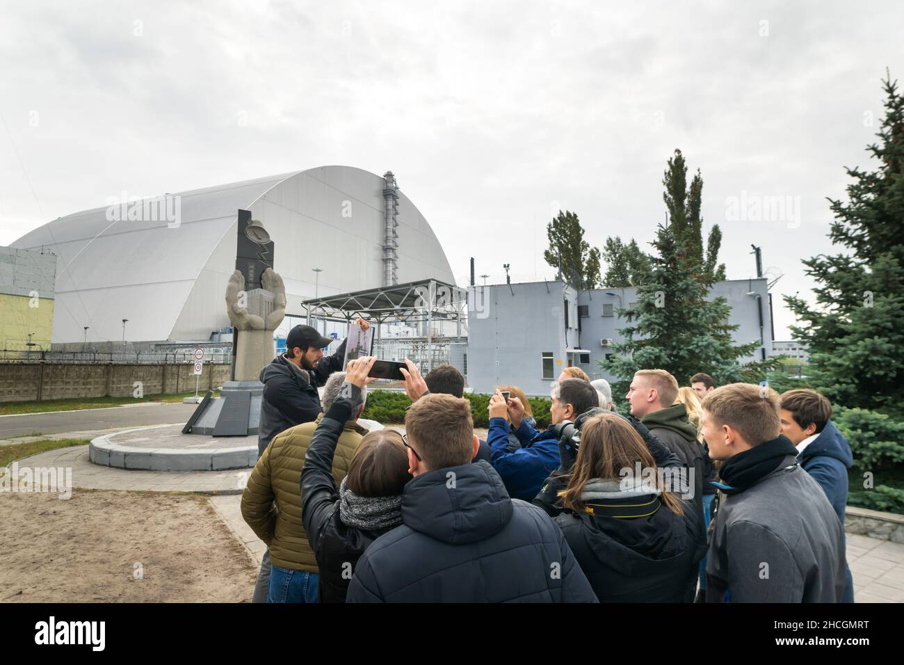 Male guide in front of Chernobyl memorial is showing a photo of nuclear ...