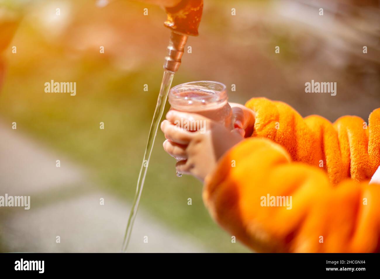 faceless child fill the glass with water in water tap outdoor Stock ...