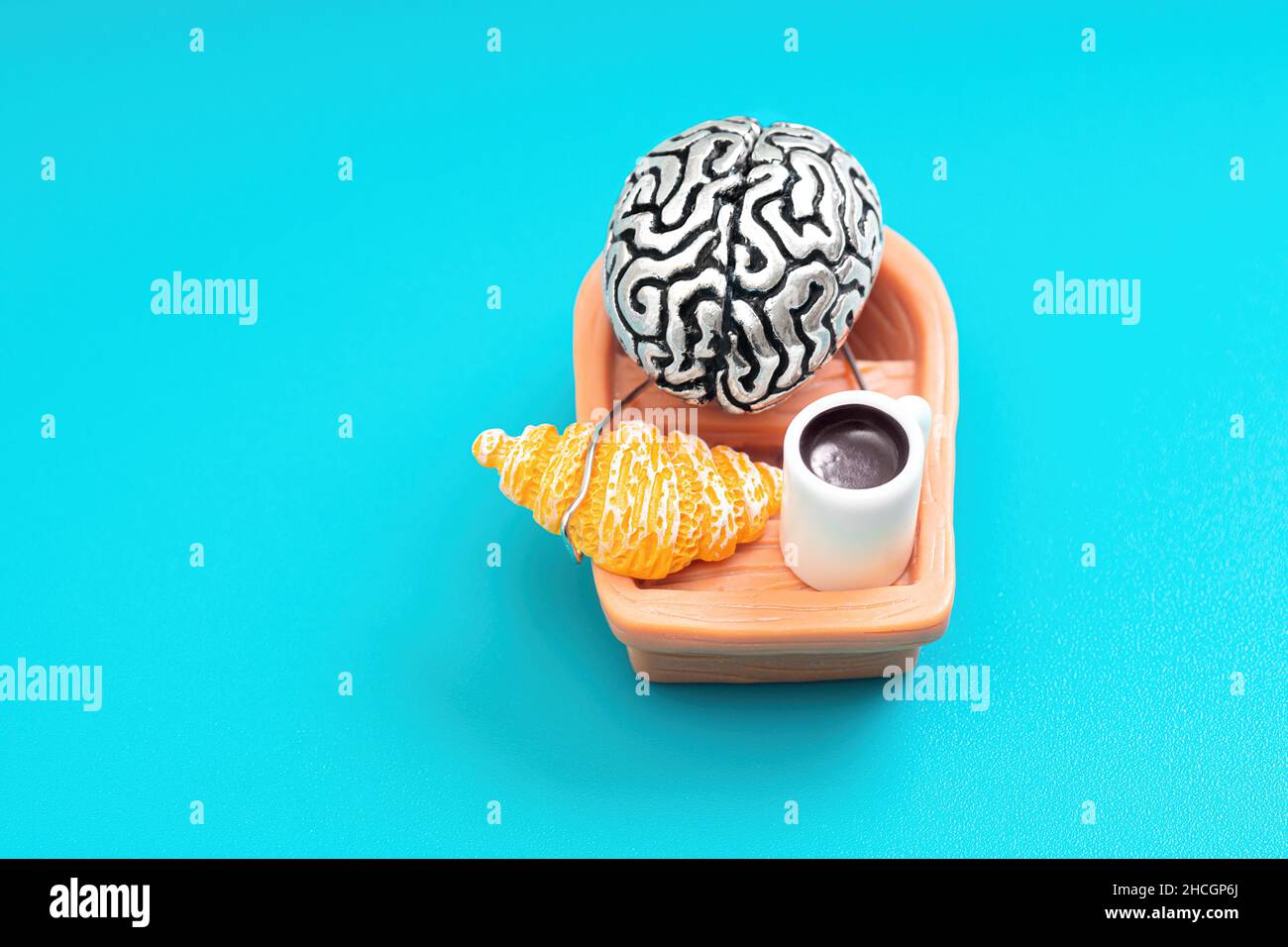 Anatomical copy of a human brain drinking coffee with croissant during ...