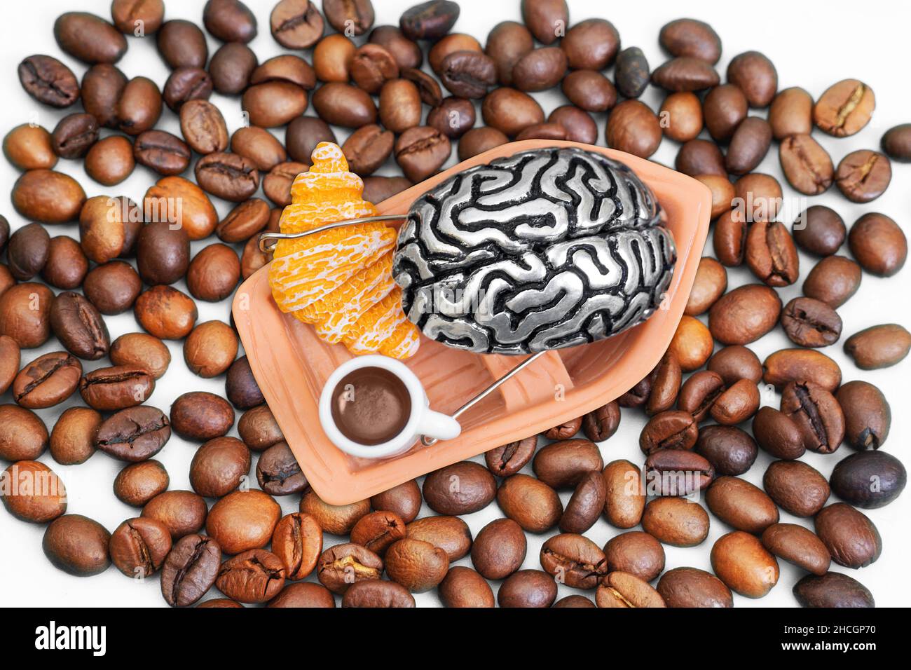 Steel copy of a human brain holding a coffee cup and a croissant while ...