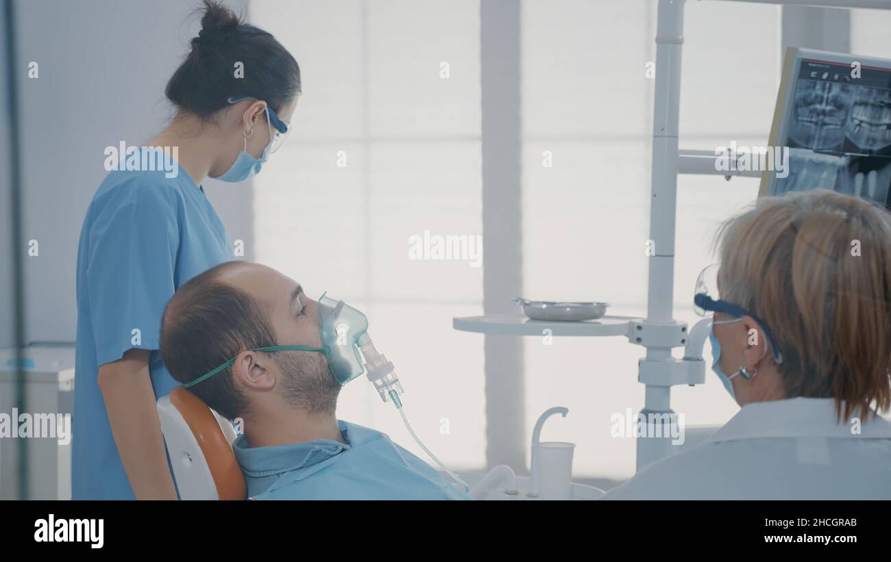 Oral care worker giving oxygen mask with anesthesic to patient. Dentist ...