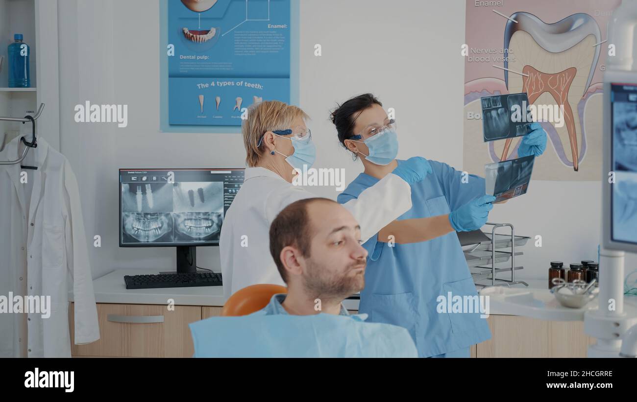 Senior dentist and nurse analyzing x ray scan to find diagnosis ...
