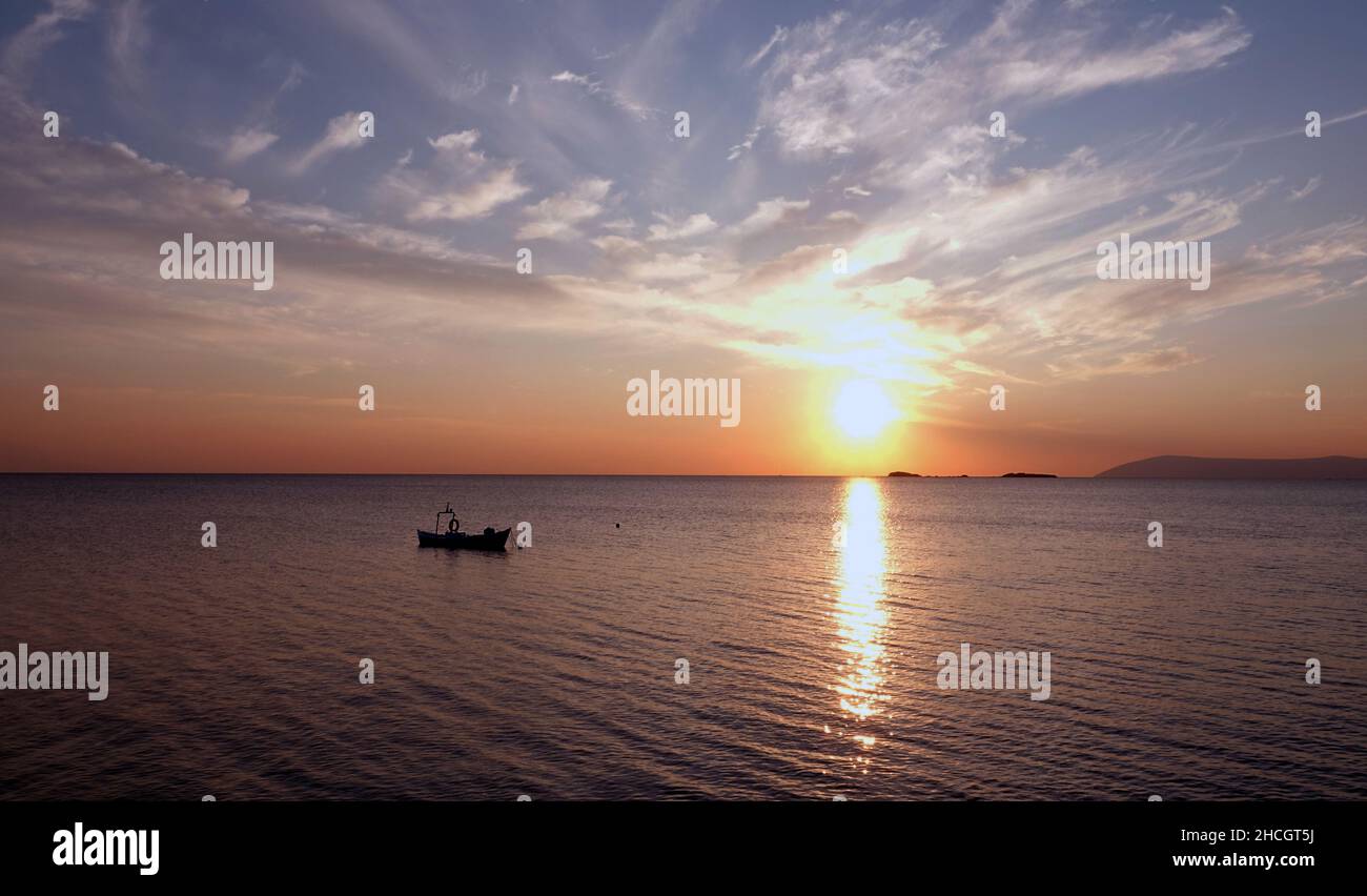 The sunset on the skyline over the sea with tiny shadow fishing boat ...