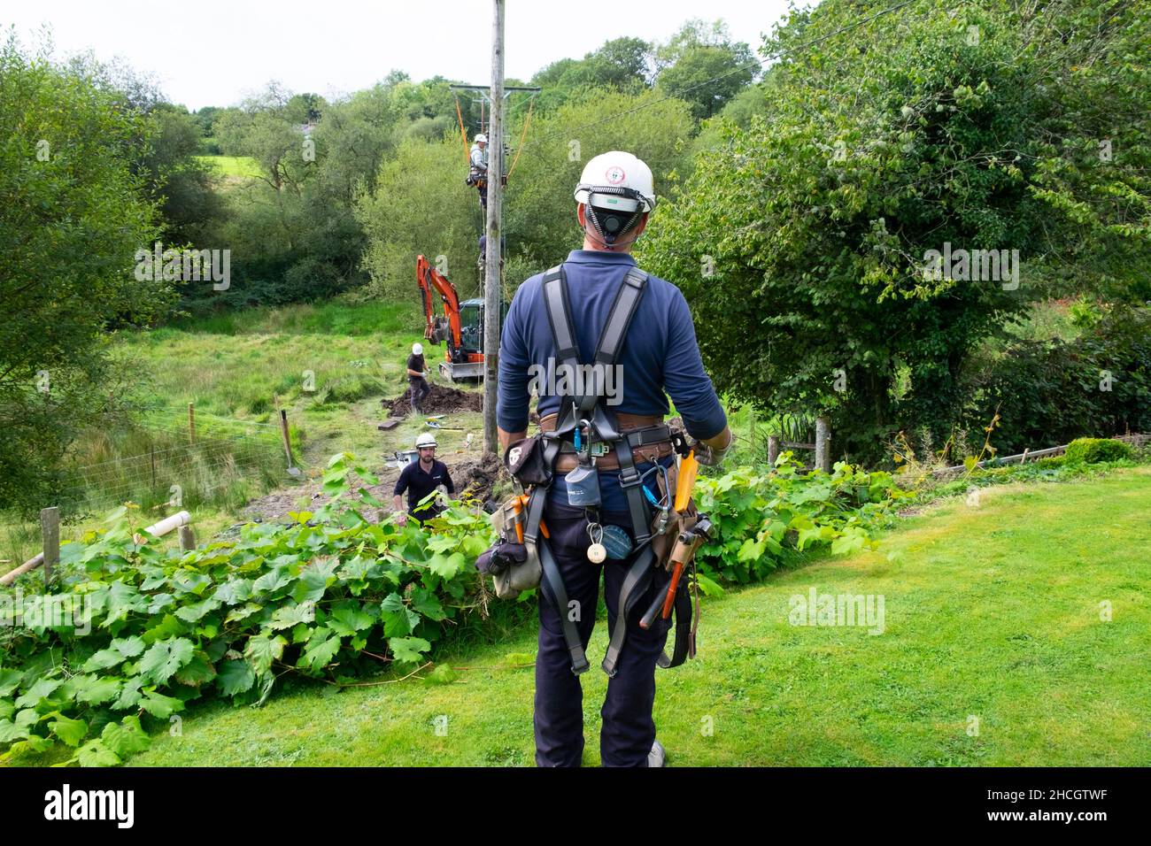 Electricity workmen working with equipment and digger putting up new ...
