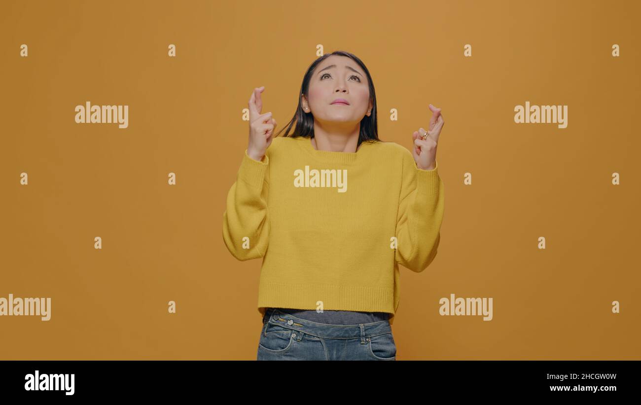 Positive adult doing praying sign with fingers crossed, asking and ...