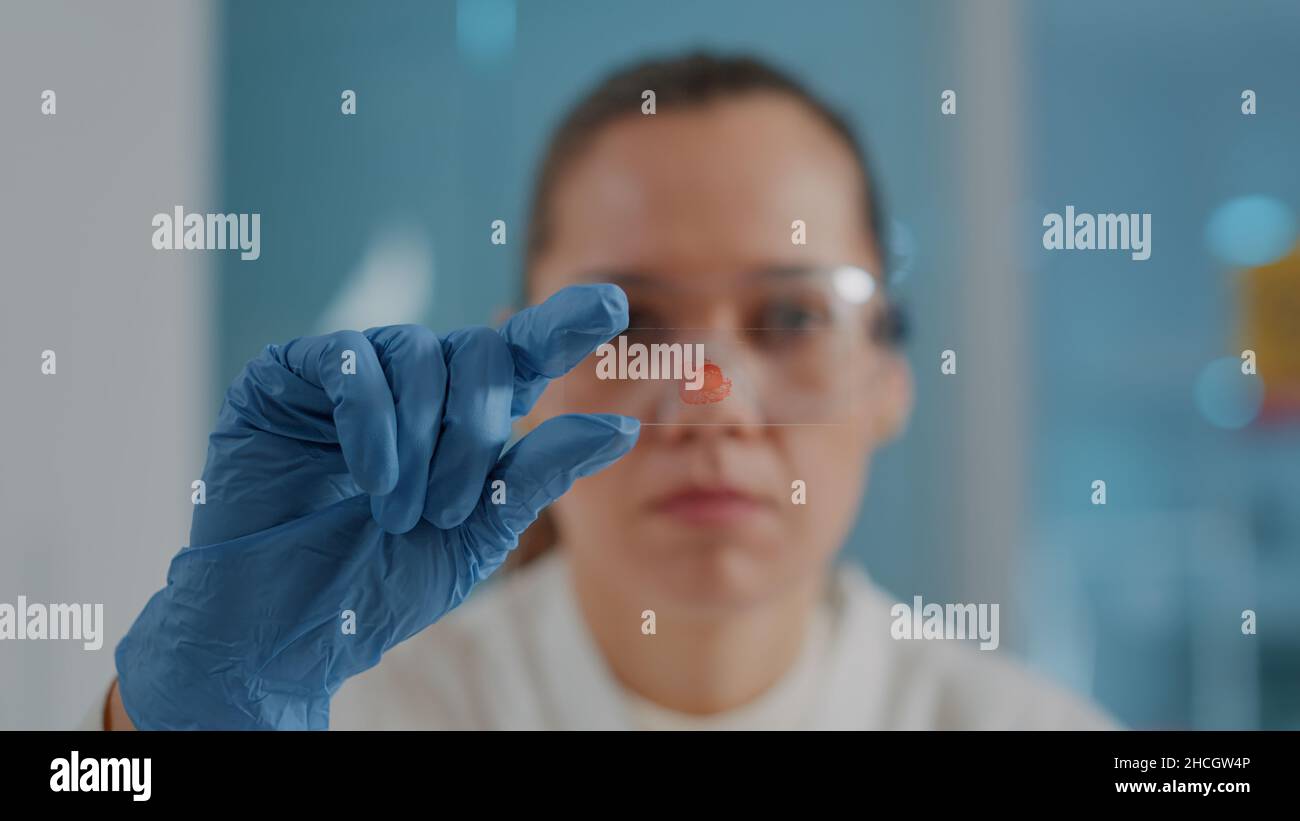 Woman analyzing blood sample on lab glassware tray in science ...