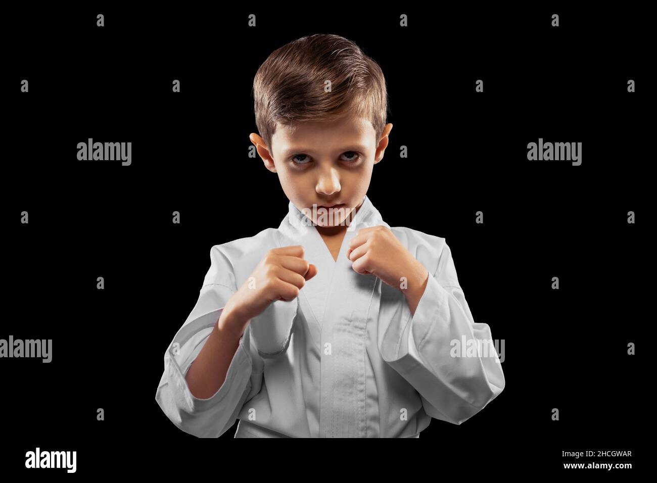 One little kid, boy, taekwondo athlete posing isolated over dark ...