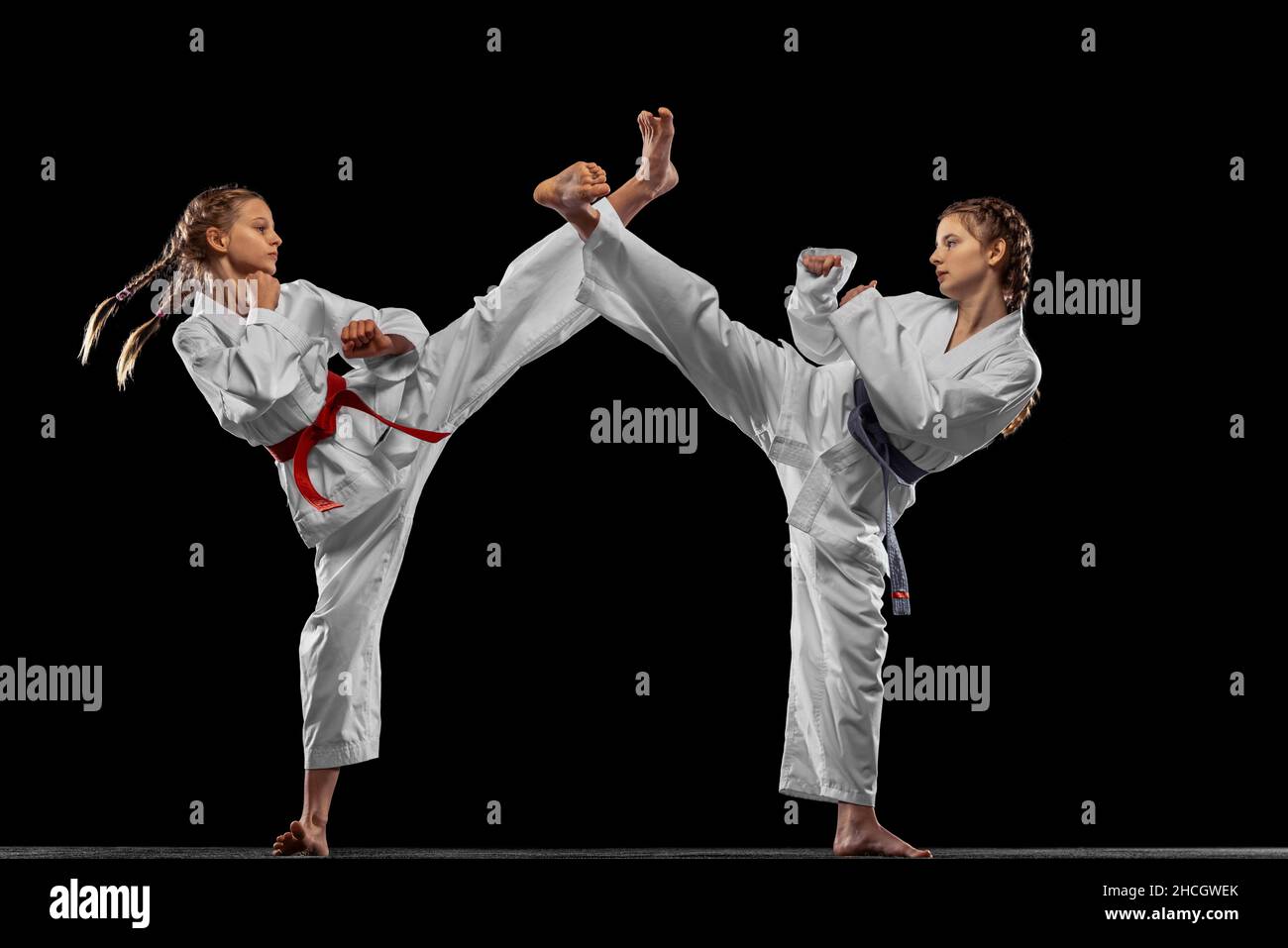 Two young girls, teens, taekwondo athletes training together isolated ...