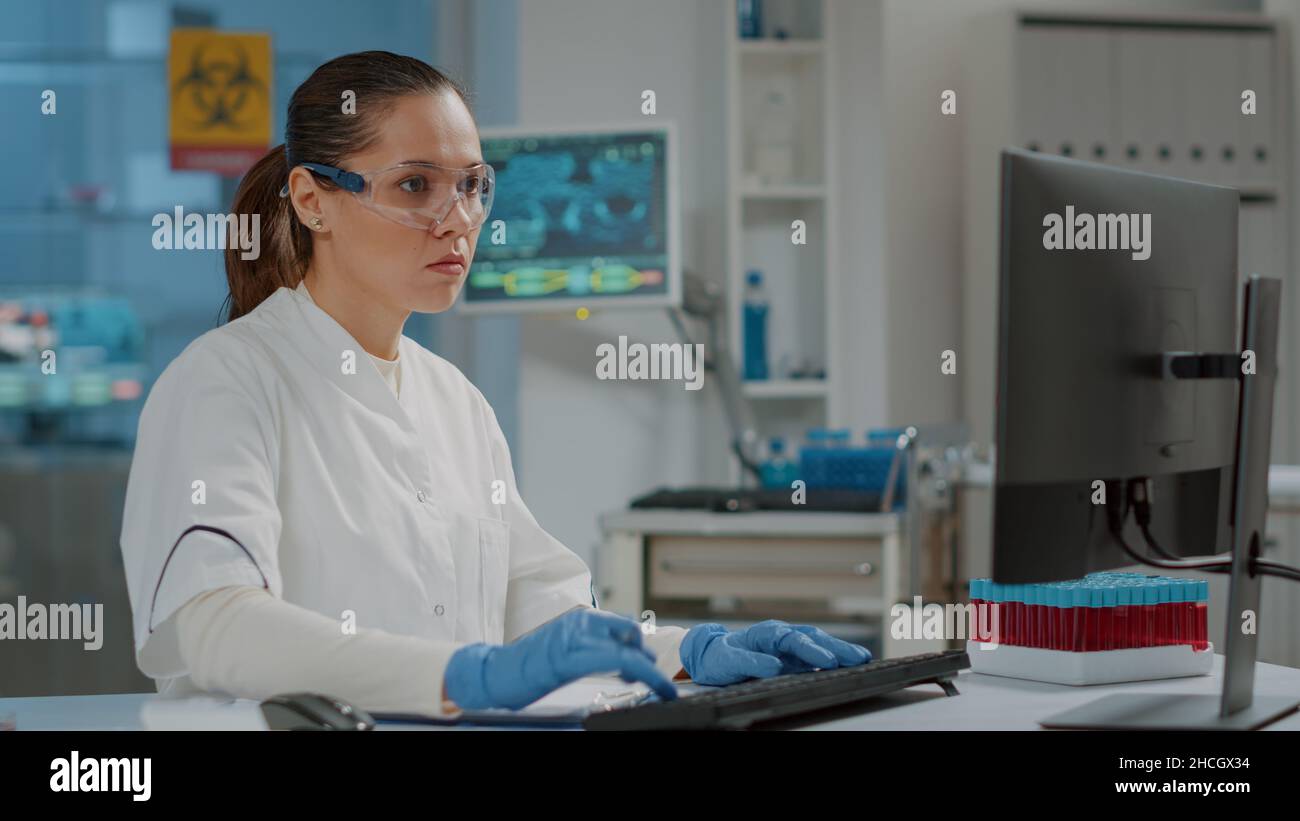Woman chemist taking notes for science research in laboratory, working ...