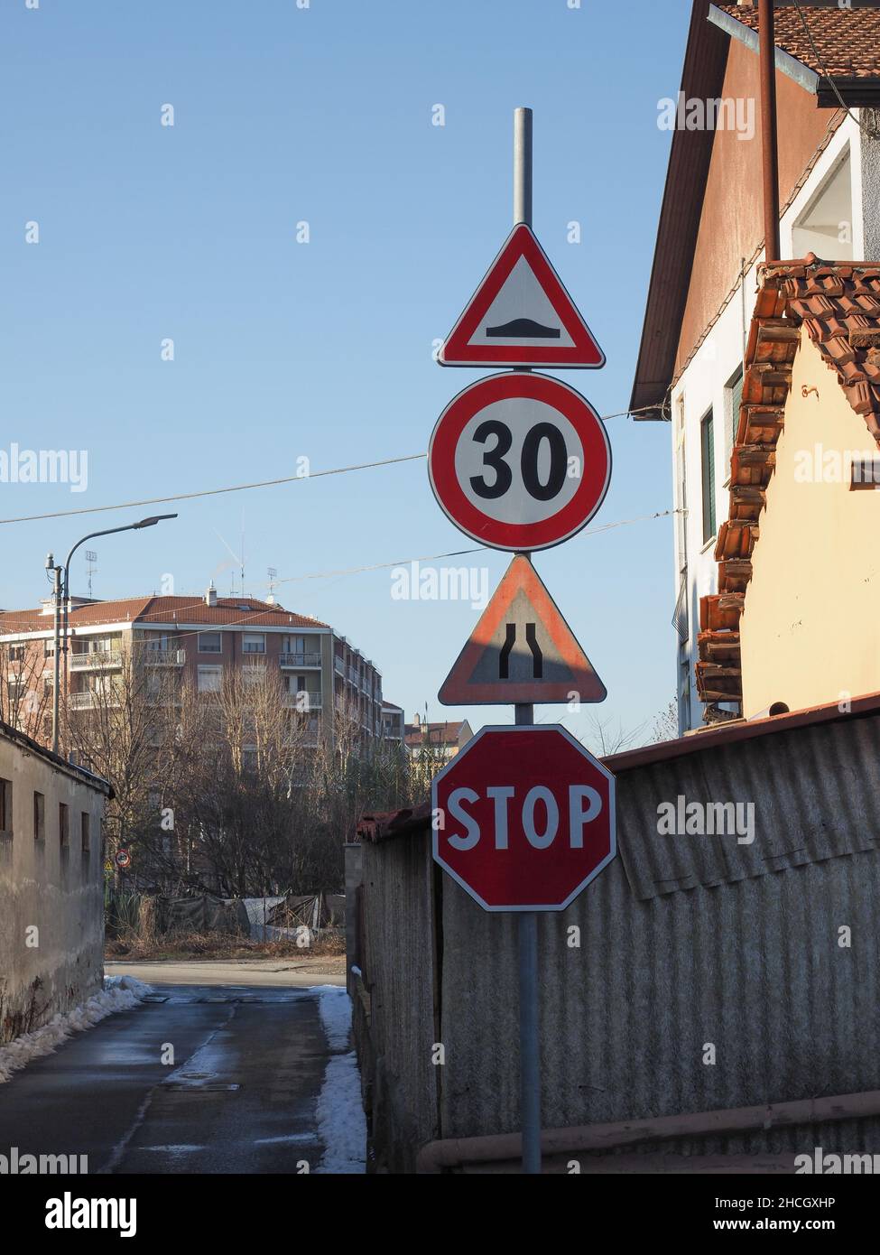 pole with many traffic signs including uneven road, speed limit, road ...