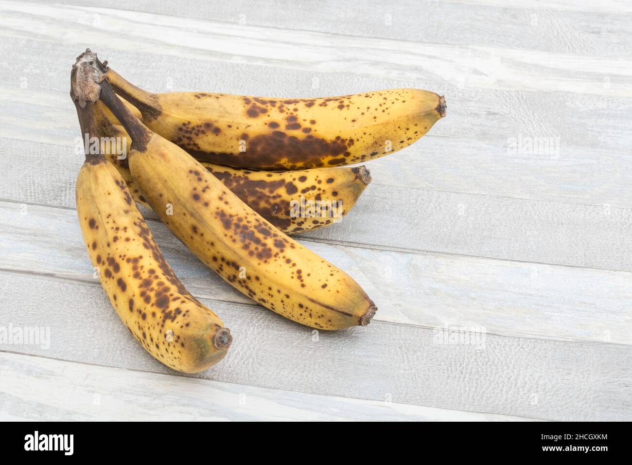 Slightly over-ripe bananas on vinyl fabric kitchen table top. For ...
