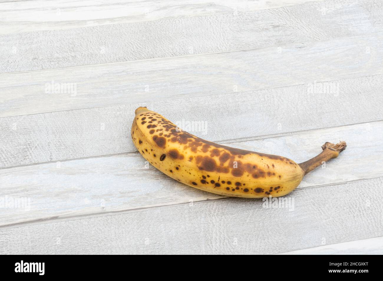 Slightly over-ripe banana on vinyl fabric kitchen table top. For common ...
