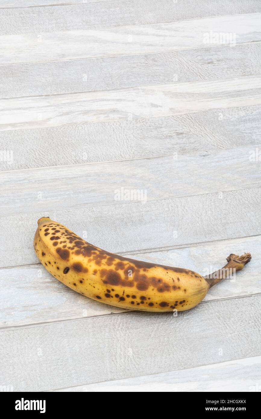 Slightly over-ripe banana on vinyl fabric kitchen table top. For common ...