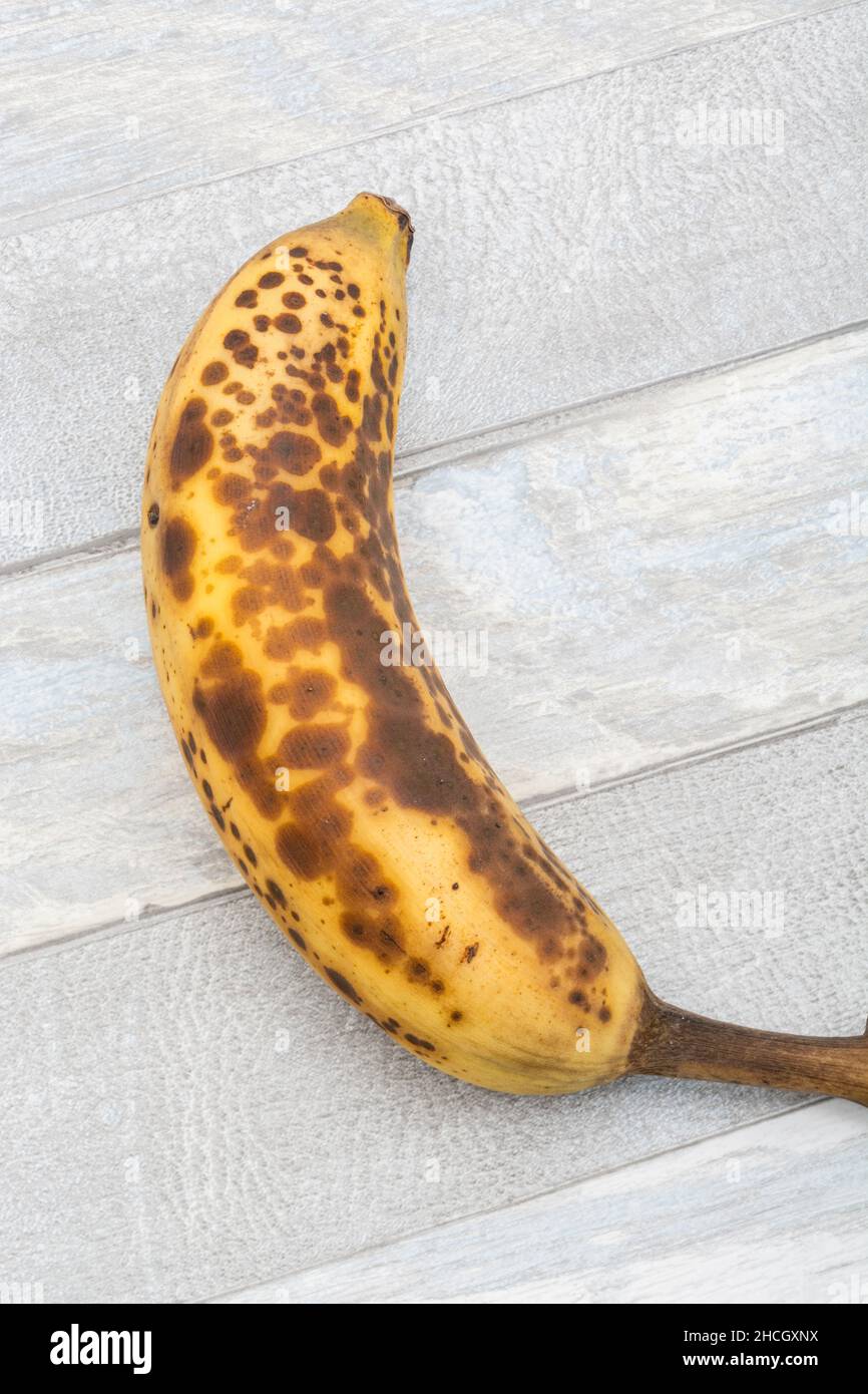 Slightly over-ripe banana on vinyl fabric kitchen table top. For common ...
