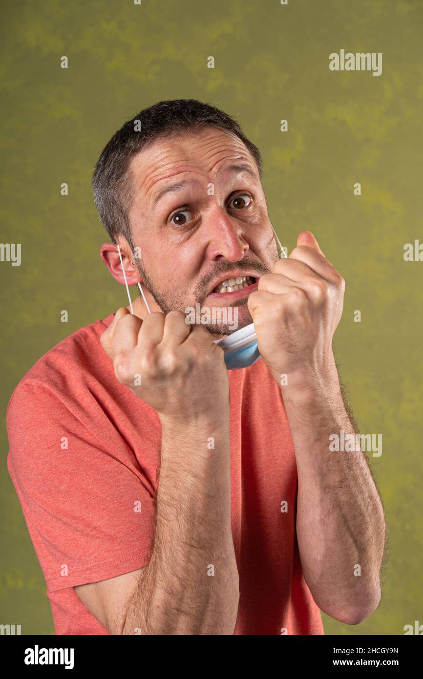 A man pulling his surgical blue mask down with anger Stock Photo - Alamy