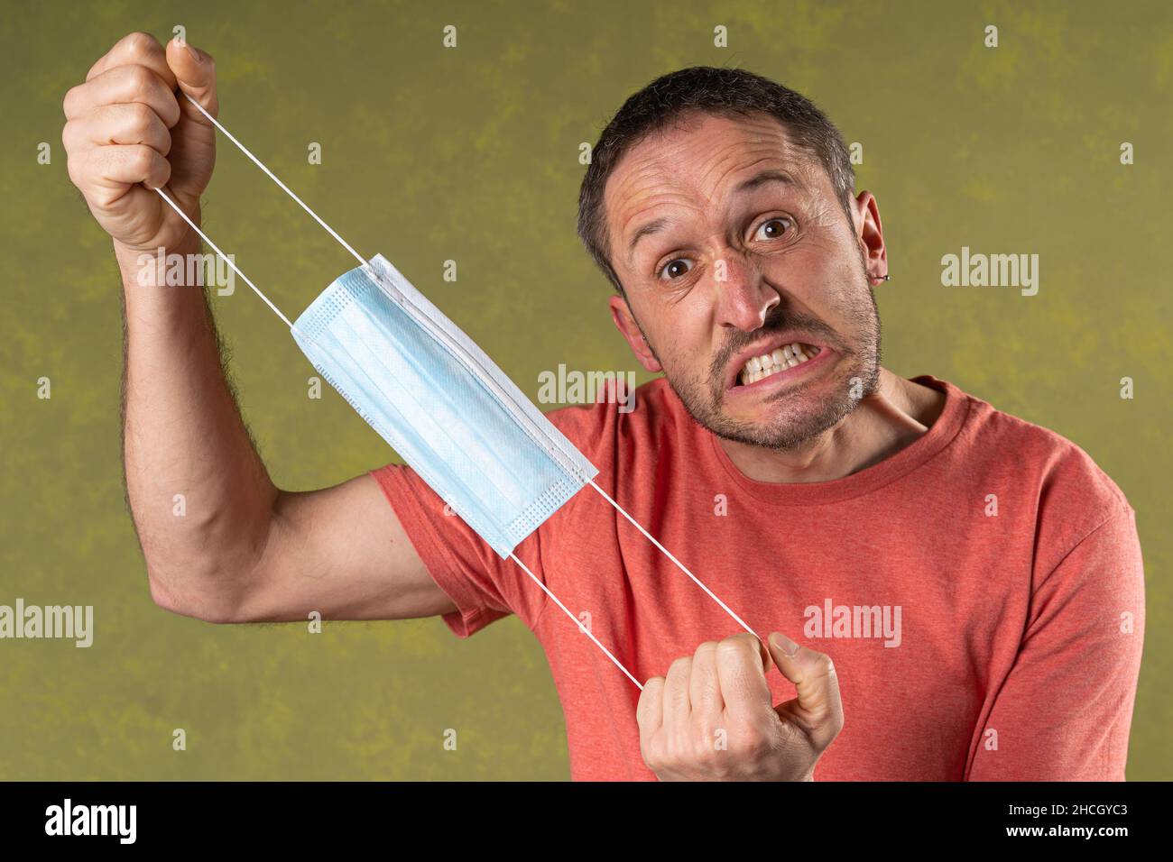 A man breaking his surgical blue mask with anger Stock Photo - Alamy