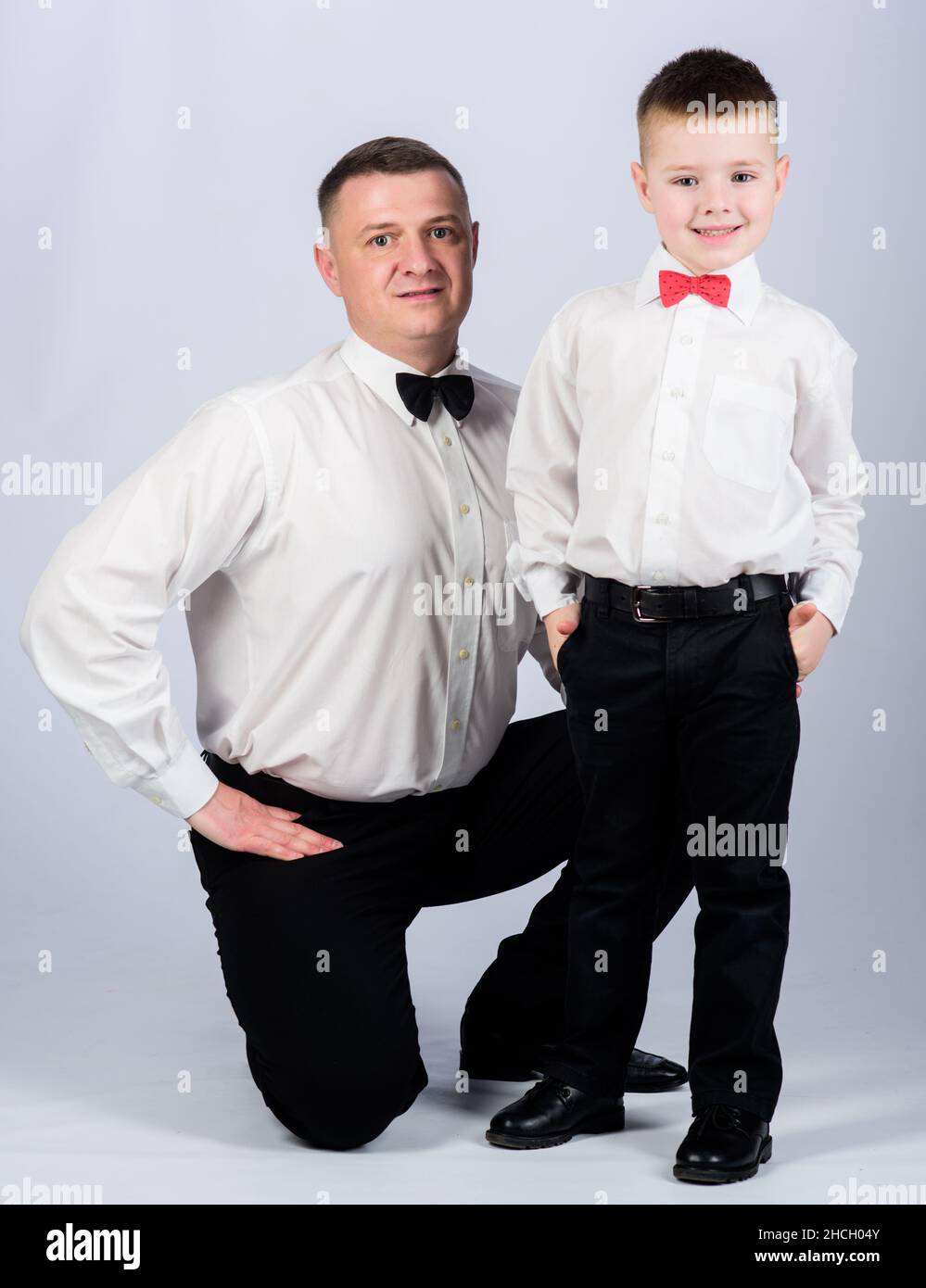 Formal event. Little son following fathers example of noble man ...