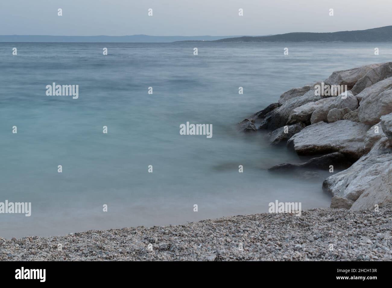 Adriatic seascape, pebble beach and rocks, hazy silhouettes of islands ...