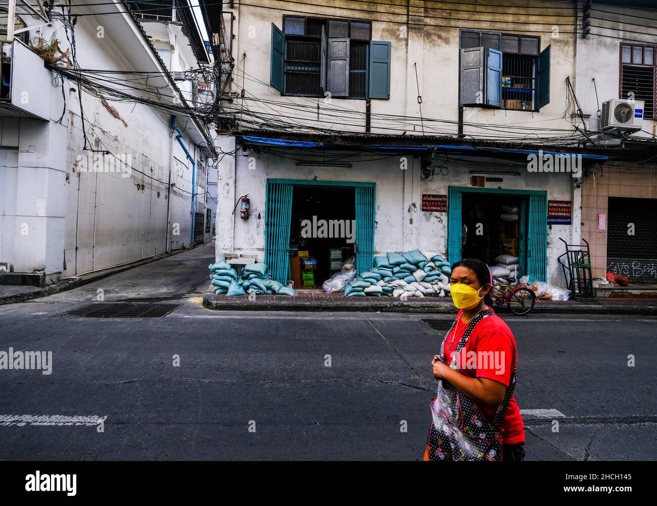 A masked woman walks past an old building in the Talat Noi area of ...