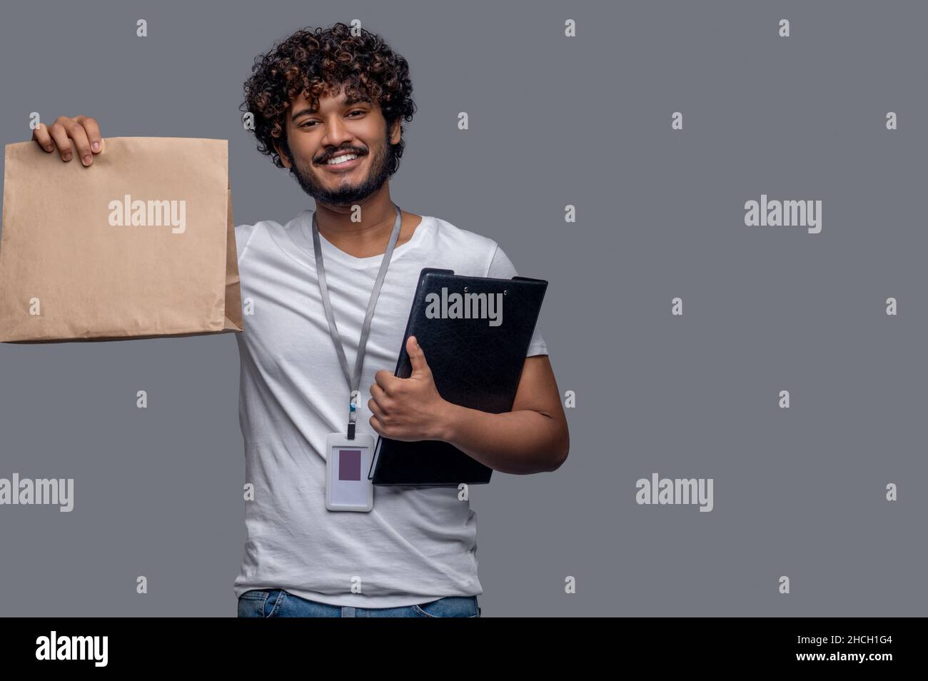 Contented delivery person with a paper bag looking ahead Stock Photo ...