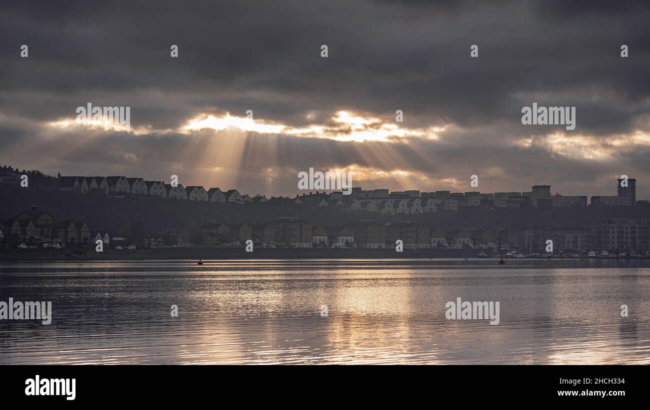Sun beams bursting through the clouds, over Penarth Marina, on the edge ...
