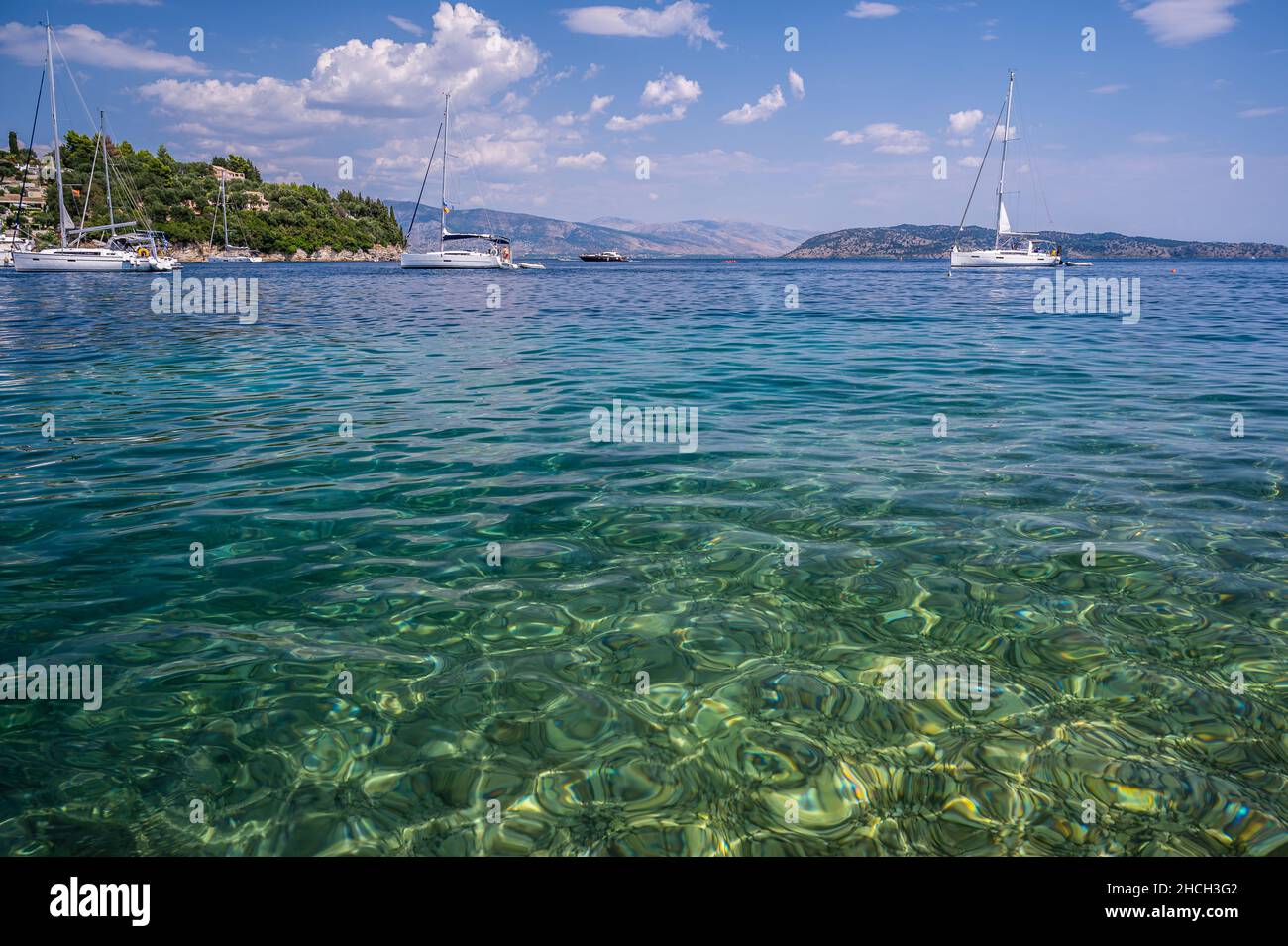The clear waters of Kalami Bay, in Corfu, Greece, on a bright summers ...