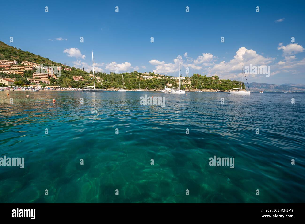 The clear waters of Kalami Bay, in Corfu, Greece, on a bright summers ...