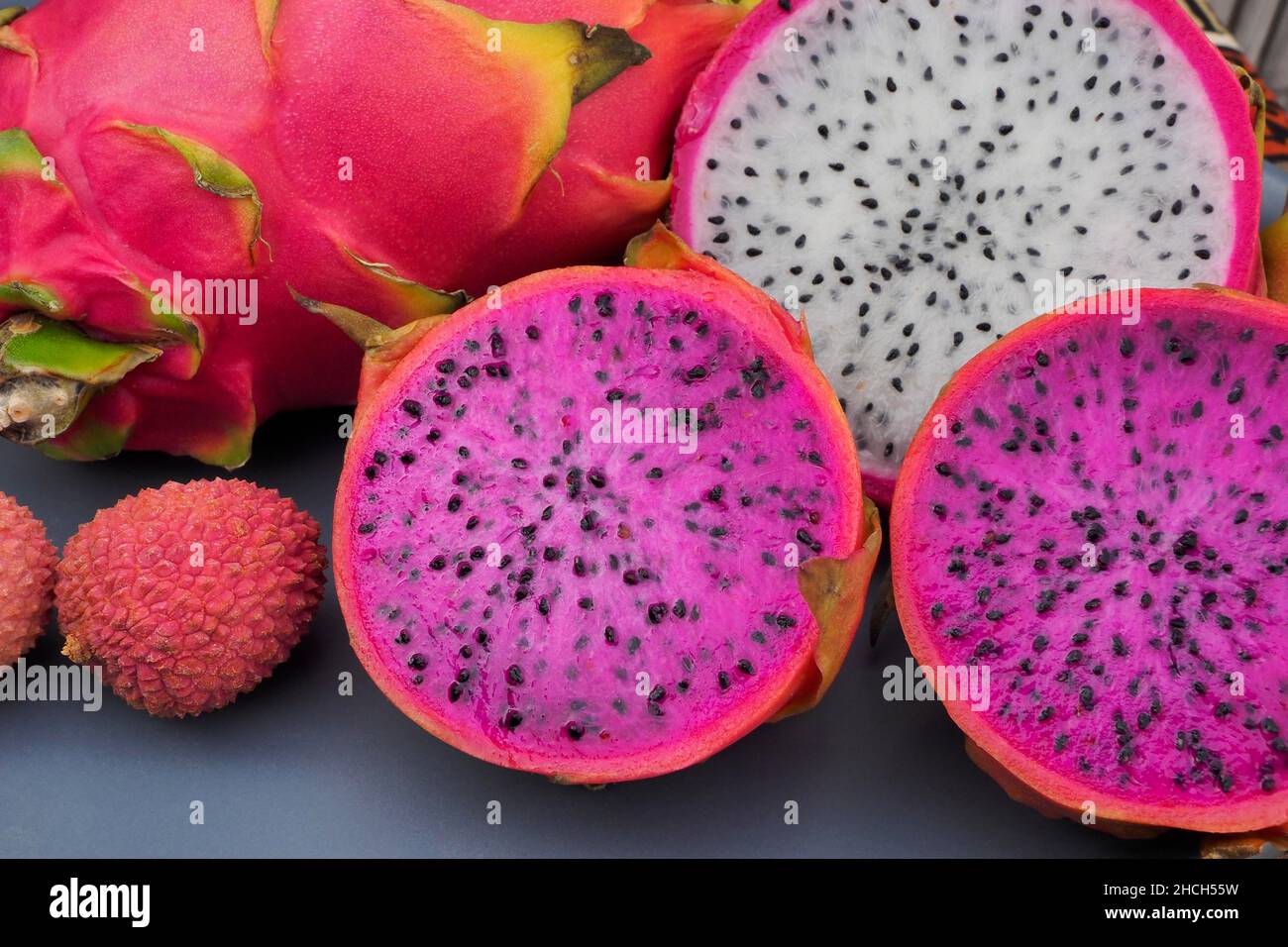 Exotic fruits, halved white and red dragon fruit (pitahaya) and lychee ...