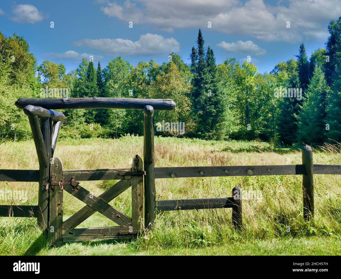 Wood fence and gate in field Stock Photo - Alamy