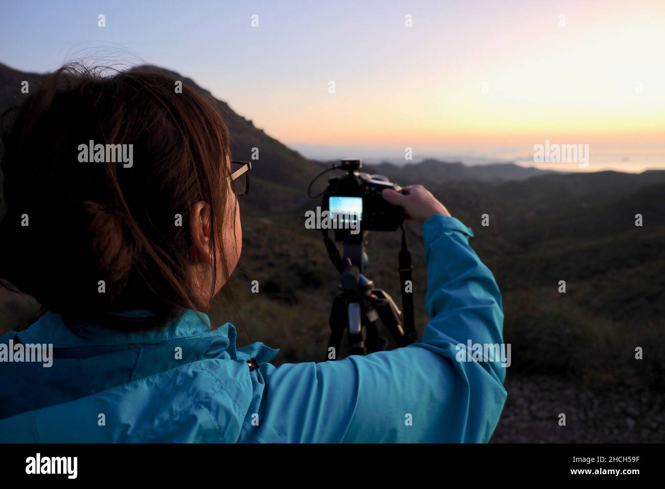 Woman taking pictures on tripod at sunrise by the sea, photographer ...
