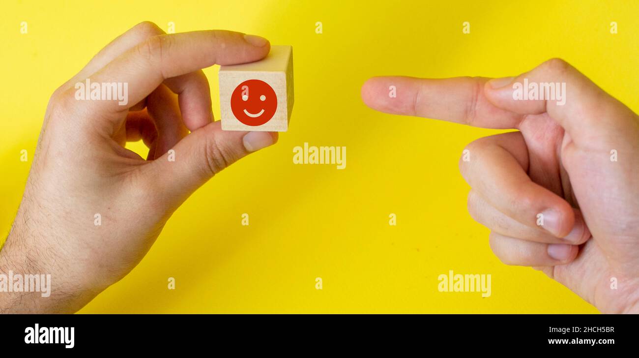 Against a yellow background, a male finger points to a cube with an ...