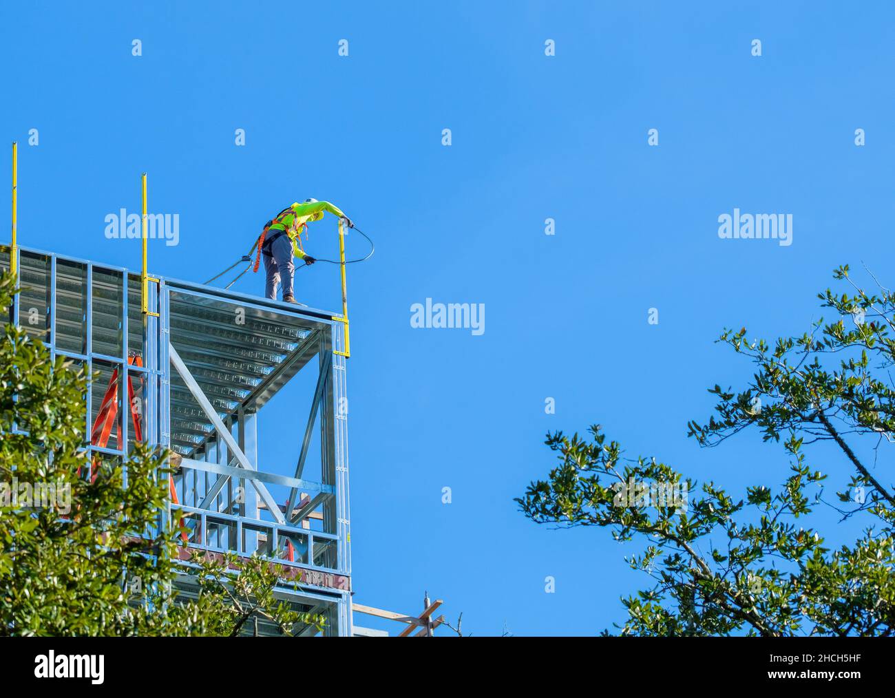 Unidentified construction worker on side of new building attaching a ...