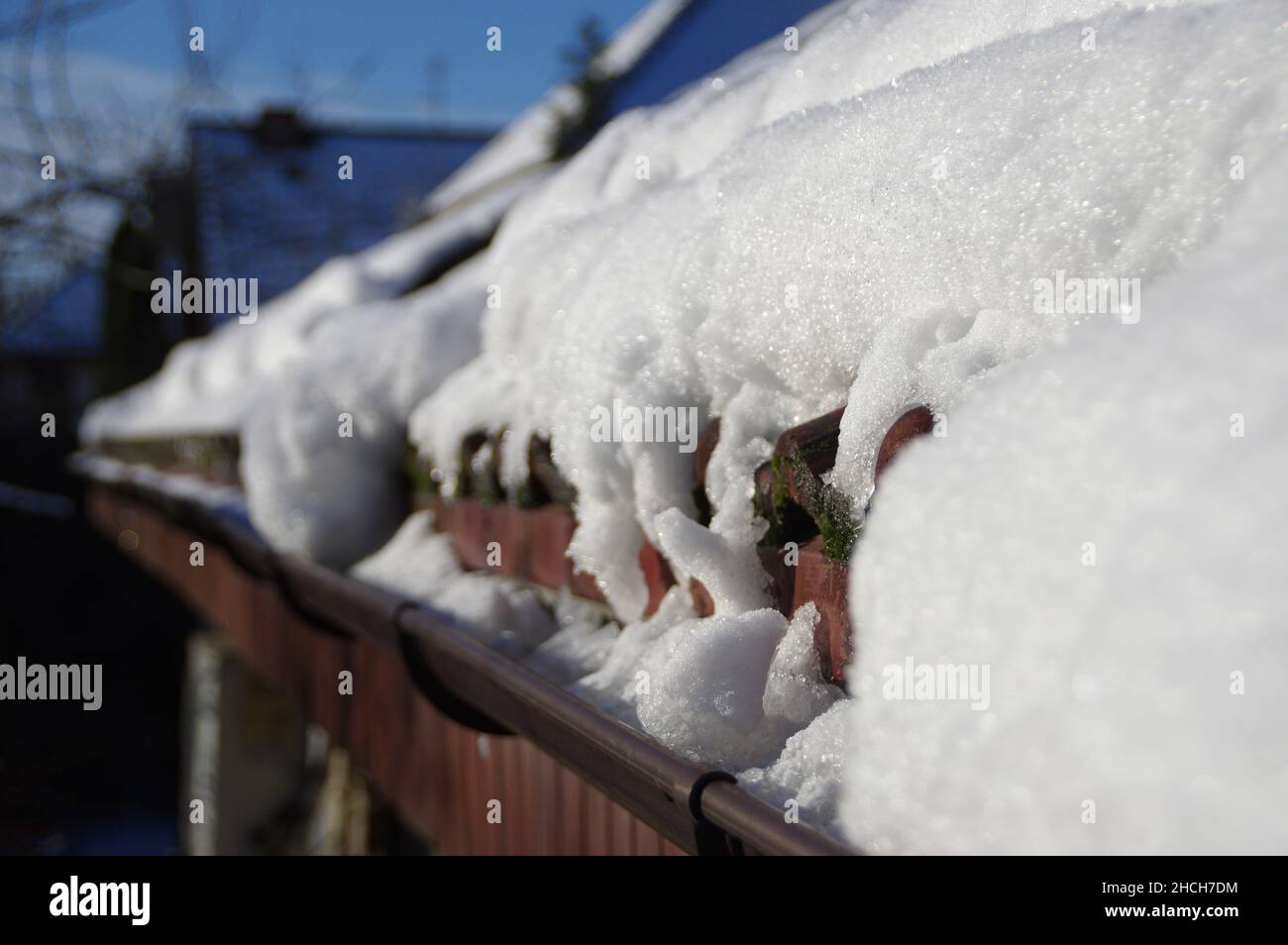Snow in the gutter during the winter season. Snowy cover on the roof of ...