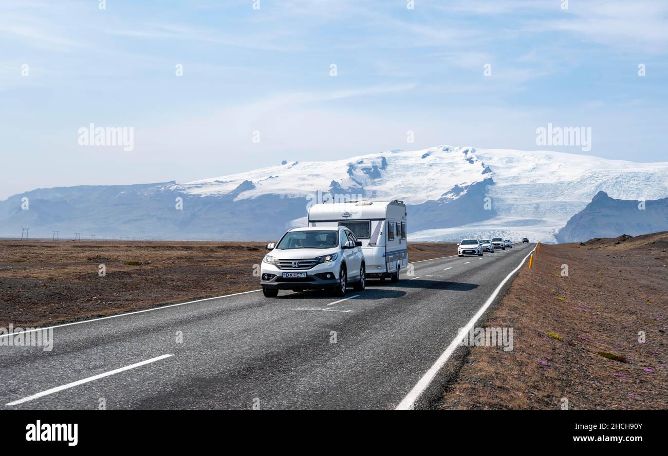 Car with caravan trailer on country road, huge Vatnajoekull glacier ...