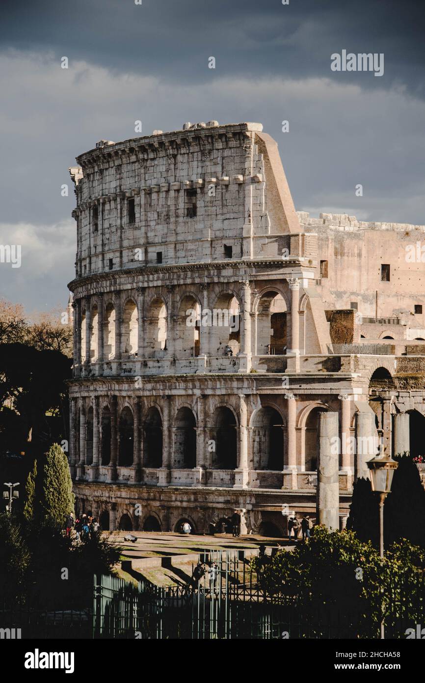 Vertical shot of the Colosseum under a cloudy sky and sunlight in Rome ...