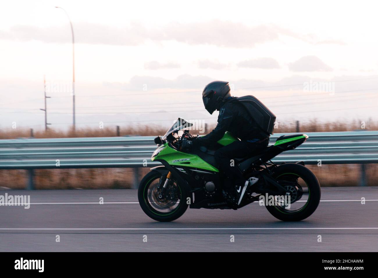 Biker riding a modern green motorcycle on the road with long exposure ...