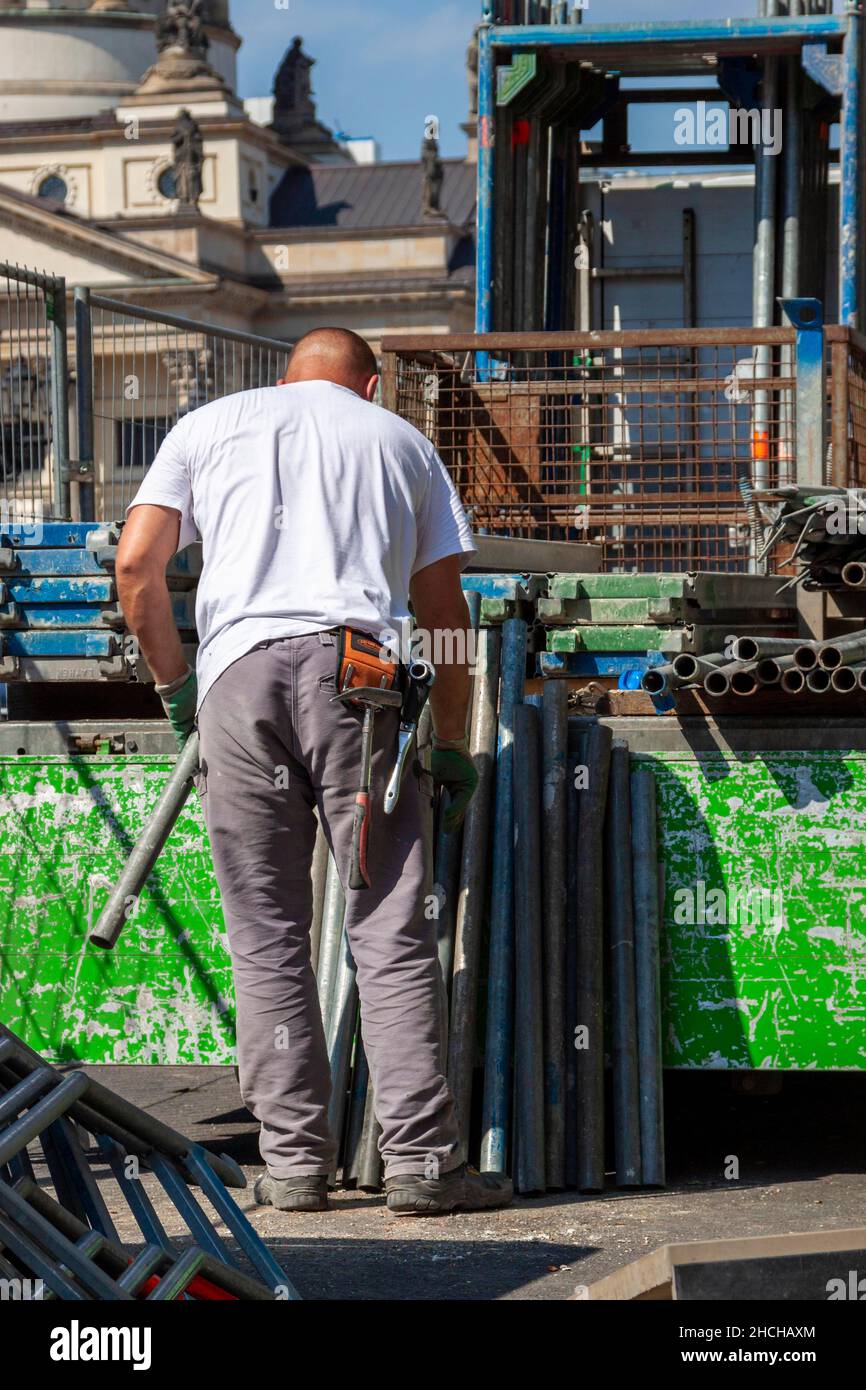 Construction worker loading a truck with scaffolding poles, Berlin ...