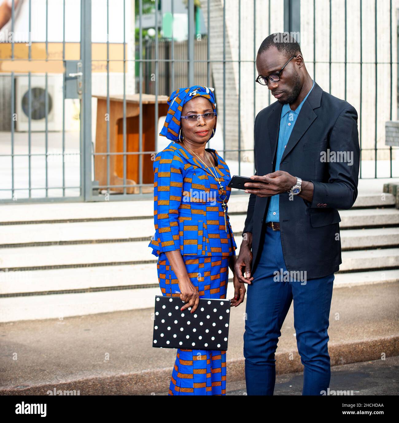 two adult business partners standing on the street using a mobile phone ...